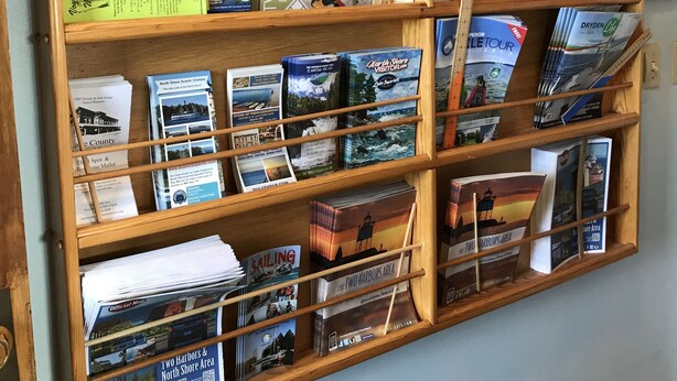 Estante de madeira com diversos folhetos de viagem e mapas.