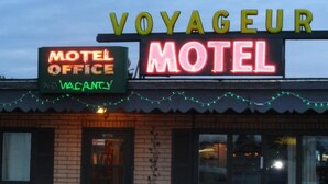 Um motel com placas de neon indicando 'Escritório do Motel' e 'Vagas'.