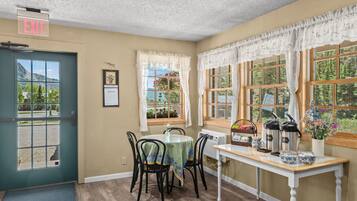 Quarto com uma mesa de jantar, cadeiras, espaço para café e vista para o exterior.