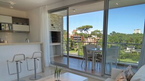Sala moderna com sofá, mesa de centro e varanda com vista para a cidade.