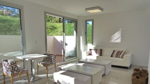 Uma sala de estar moderna com um sofá branco, duas mesinhas de centro brancas e cadeiras estampadas.
