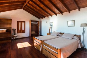 Quarto com cama de madeira, uma cadeira, guarda-roupa e luminária de chão.
