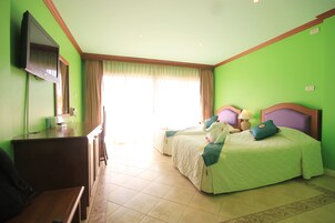 Quarto de hotel com duas camas, uma escrivaninha, uma televisão e uma janela com cortinas.