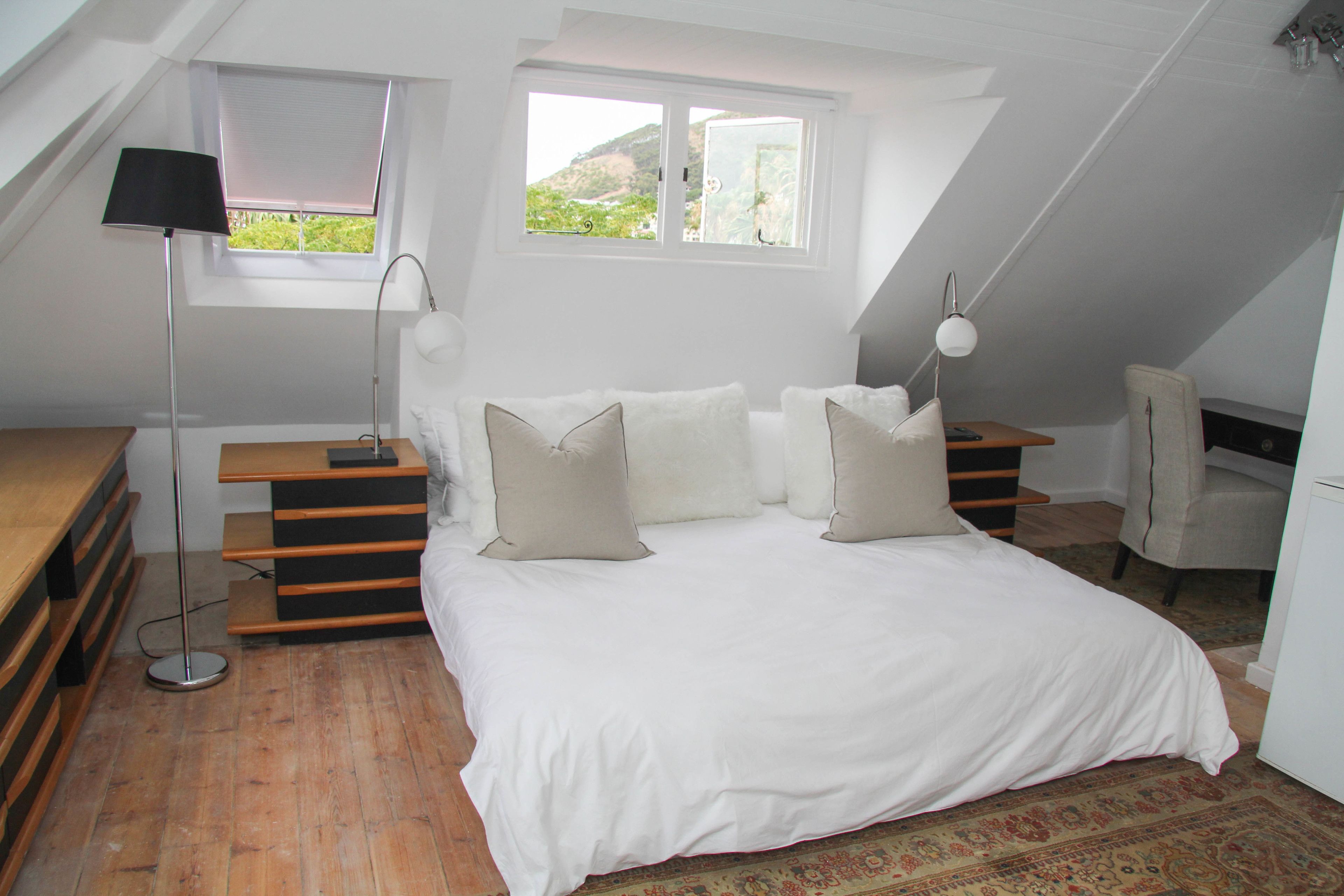 Quarto com cama, escrivaninha, cadeira, luminária e janela.