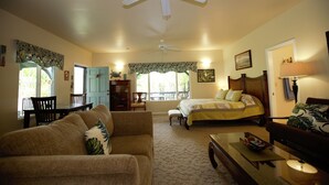 Uma sala de estar ampla com uma cama grande, um sofá, uma mesa de centro e uma área de jantar com cadeiras e mesa.