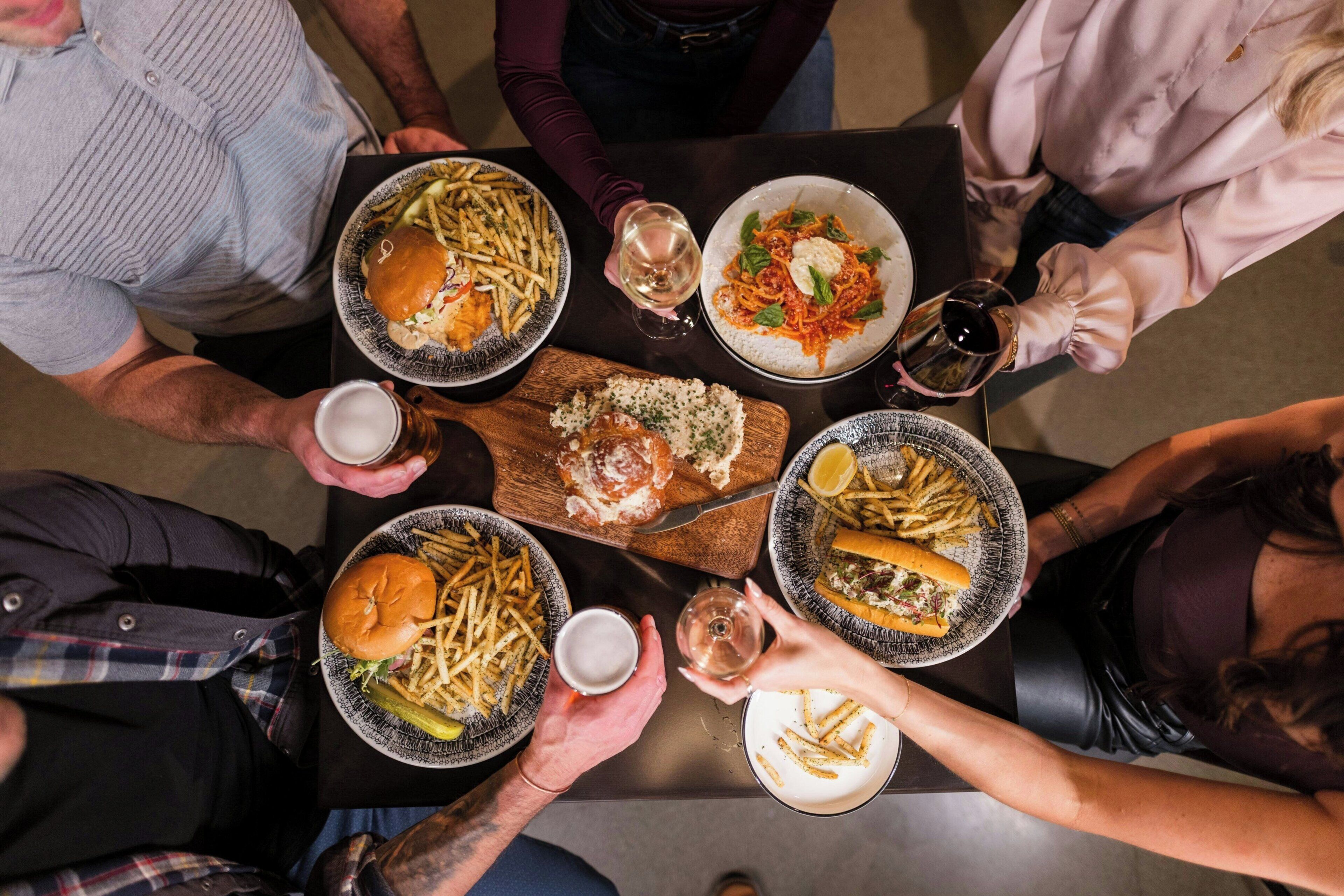 Um grupo de pessoas reunido em torno de uma mesa com comida e bebidas.