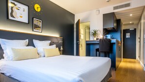Quarto de hotel moderno com uma cama grande, uma escrivaninha e um espelho.
