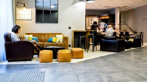 Um lobby moderno com sofá, pufes e área de refeições.