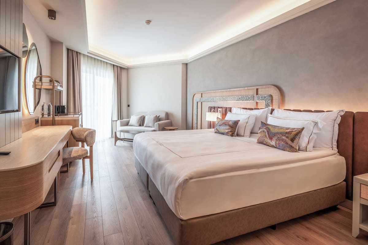 Quarto de hotel moderno com uma cama grande, uma mesa, uma cadeira e uma televisão.