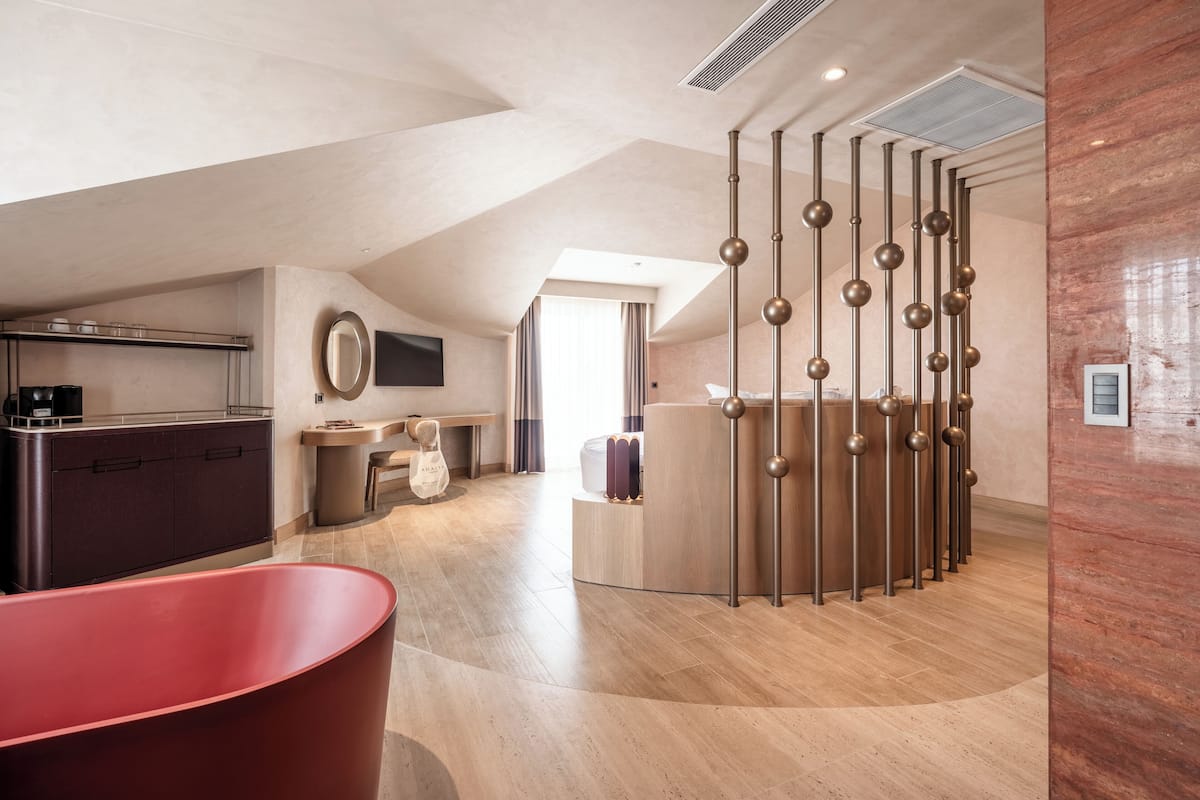Interior moderno de hotel com cozinha, uma banheira vermelha e um design de parede único com elementos esféricos suspensos.