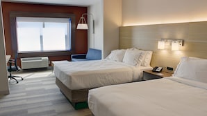 Quarto de hotel com duas camas, uma escrivaninha, uma cadeira, um abajur e uma janela.