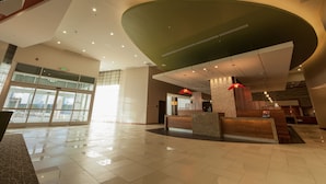Um hall amplo com balcão de recepção, grandes janelas e design moderno no teto.