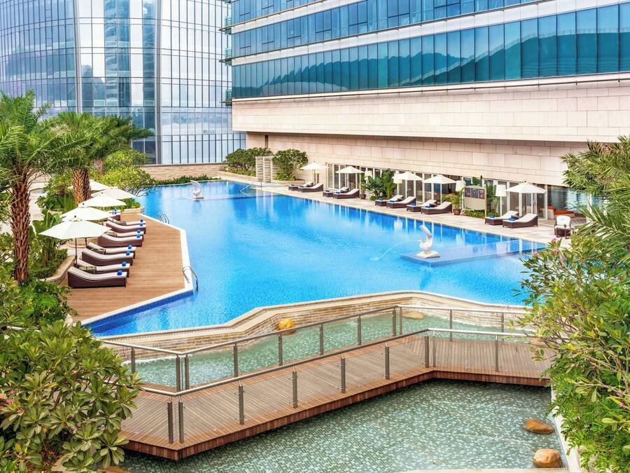 Um hotel moderno com uma grande piscina interior, espreguiçadeiras e um deque de madeira.
