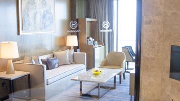 Quarto de hotel moderno com uma banheira grande, um sofá, uma mesa de centro e um espaço para refeições.