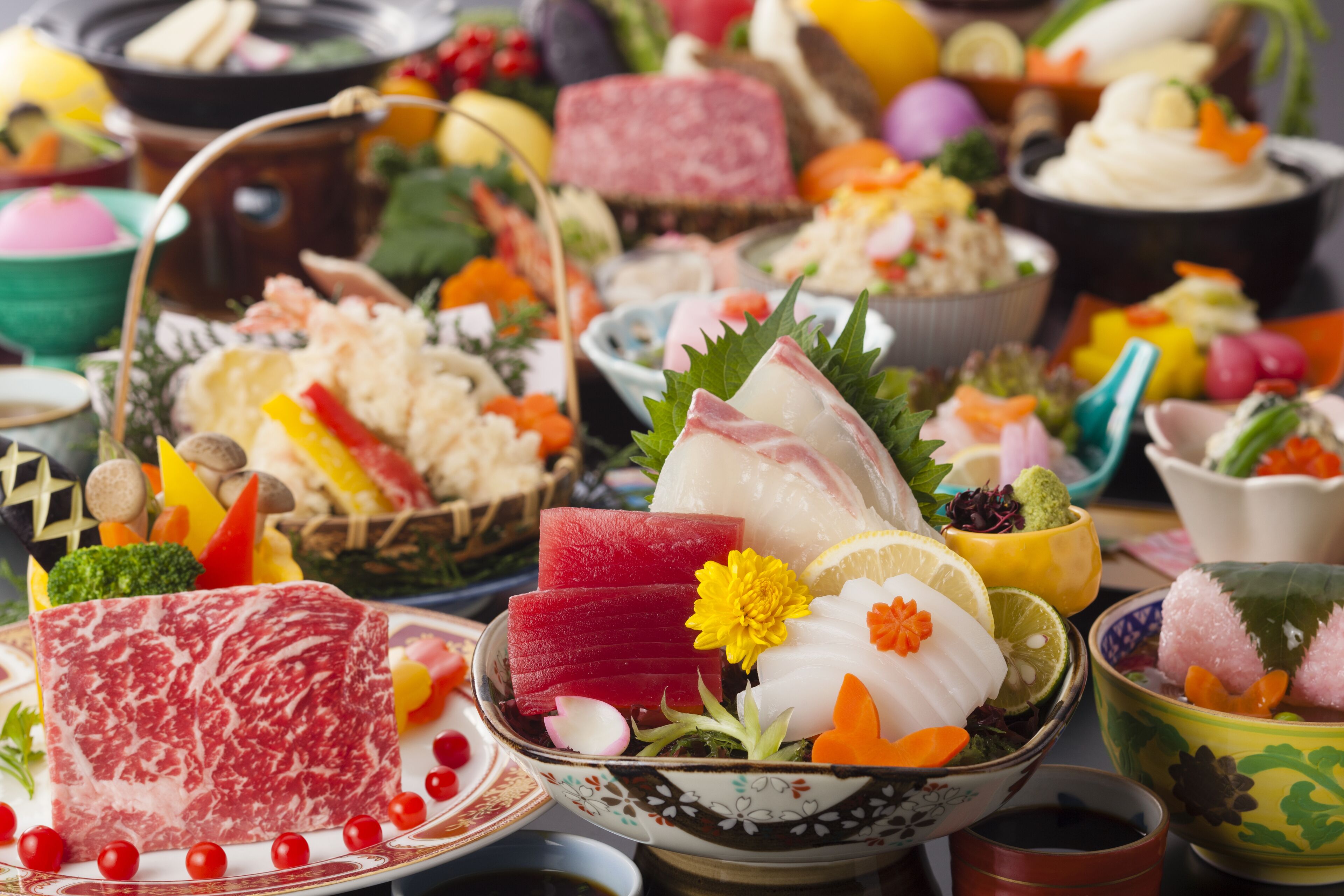 Diversos pratos de comida, incluindo sashimi, legumes e outras opções, dispostos sobre uma mesa.