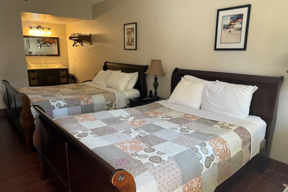 Quarto de hotel com duas camas, banheiro e um pequeno espaço para sentar.