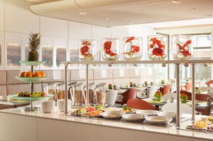 Disposição de buffet com diversos alimentos e flores decorativas em recipientes de vidro.