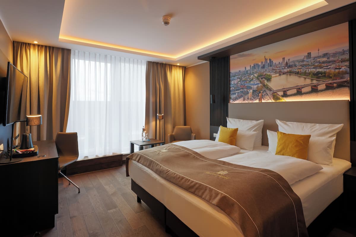 Quarto de hotel com uma cama grande, uma escrivaninha, uma cadeira e vista para a cidade.