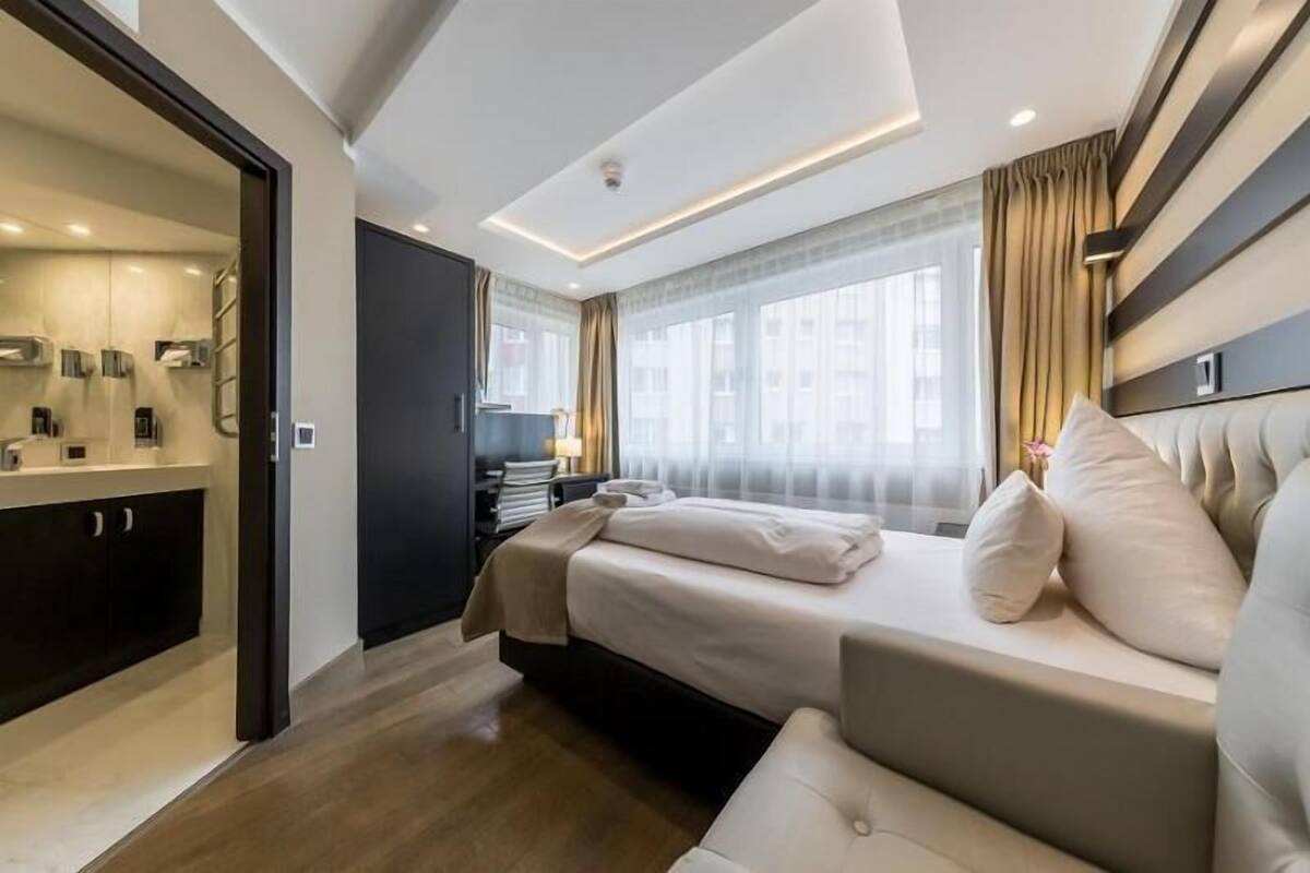 Quarto de hotel moderno com cama, mesa de cabeceira e vista para a cidade.