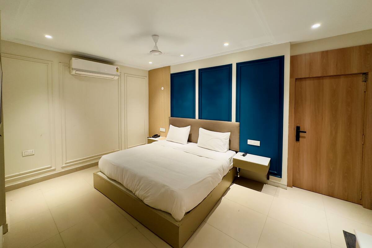 Quarto moderno com cama grande, mesa de cabeceira, ar condicionado e guarda-roupa de madeira.