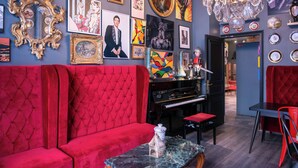 Um quarto com um sofá vermelho estofado, um piano preto e uma mesa de centro de mármore.