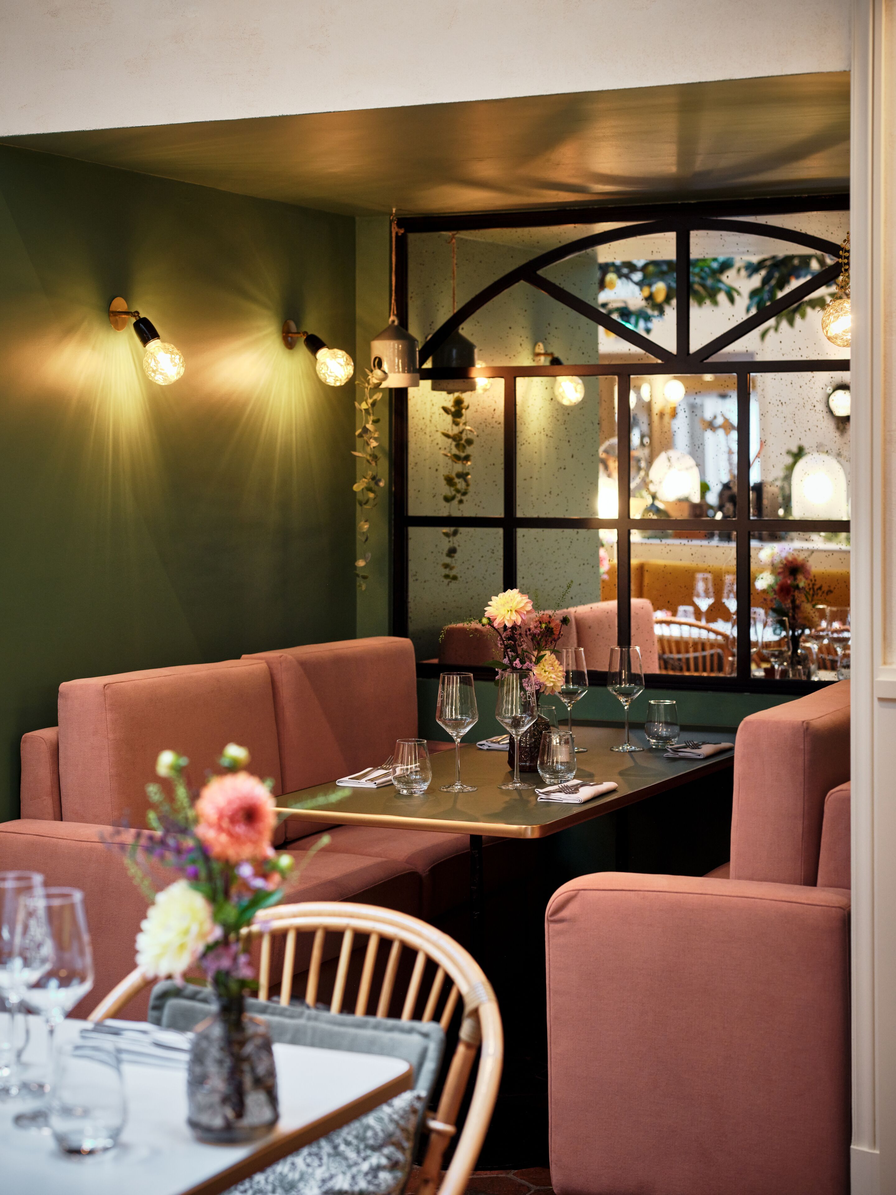 Interior de restaurante com cabines, uma mesa posta para refeição e luminárias pendentes.