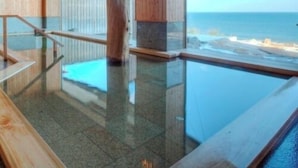 Interior em madeira com piscina infinita de vidro, vigas de madeira e vista para o oceano.
