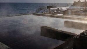 Uma área de águas termais com um deck de madeira e estruturas de pedra.