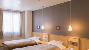 Quarto de hotel com três camas, uma mesa de cabeceira com telefone e uma janela com cortinas.