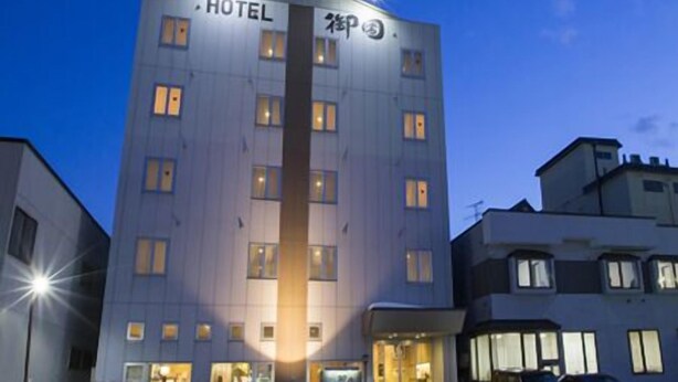 Um edifício de hotel com uma placa que diz 'HOTEL' e um logotipo acima da entrada.