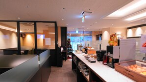 Um hall de hotel moderno com balcão de recepção, árvore de Natal e área de buffet com diversos alimentos e uma máquina de café.