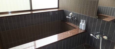 Casa de banho com uma banheira grande, chuveiro e espelho.