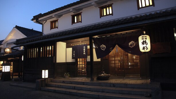 Um edifício japonês tradicional com fachada de madeira, telhado de telhas e uma placa com caracteres japoneses.