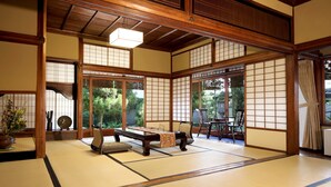 Um quarto japonês tradicional com tatames, uma mesa de madeira baixa e portas deslizantes.