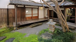 Um edifício no estilo tradicional japonês, com um deque de madeira, um farol de pedra e um jardim de cascalho.