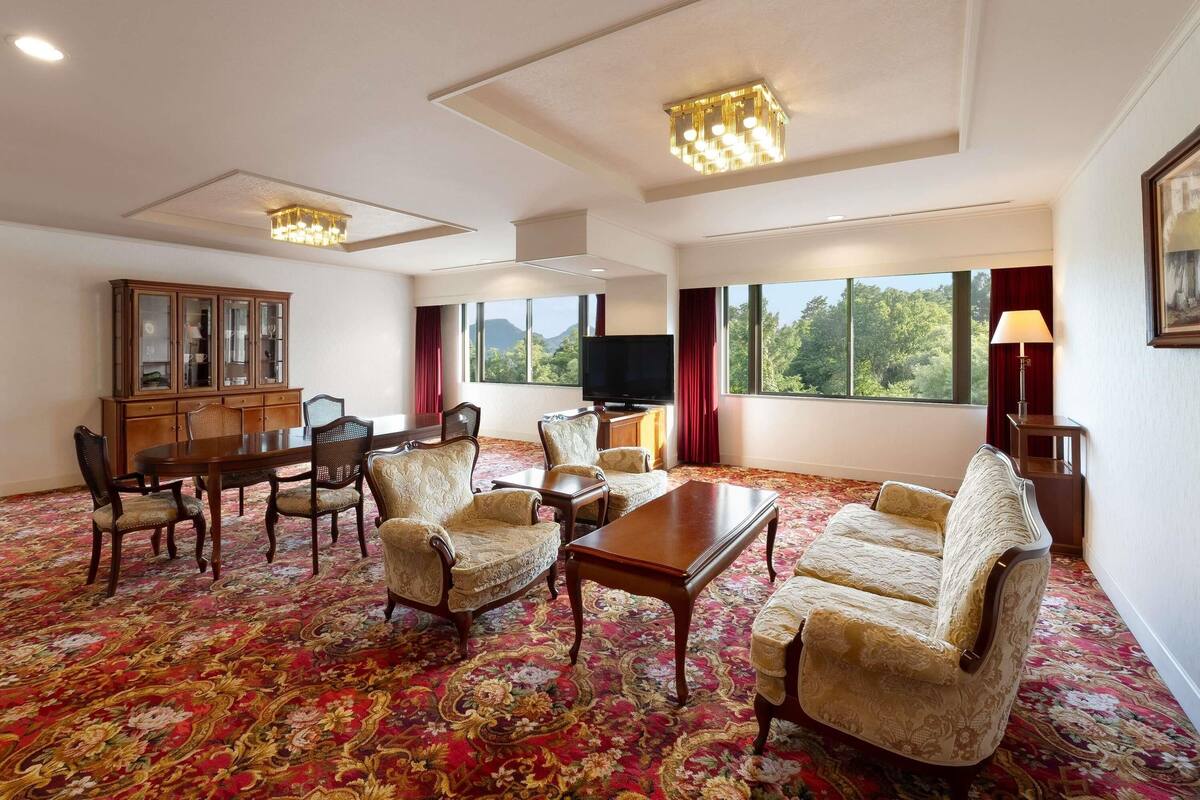 Quarto de hotel espaçoso com uma grande mesa de jantar, assentos confortáveis, televisão de tela plana e vista para o exterior.