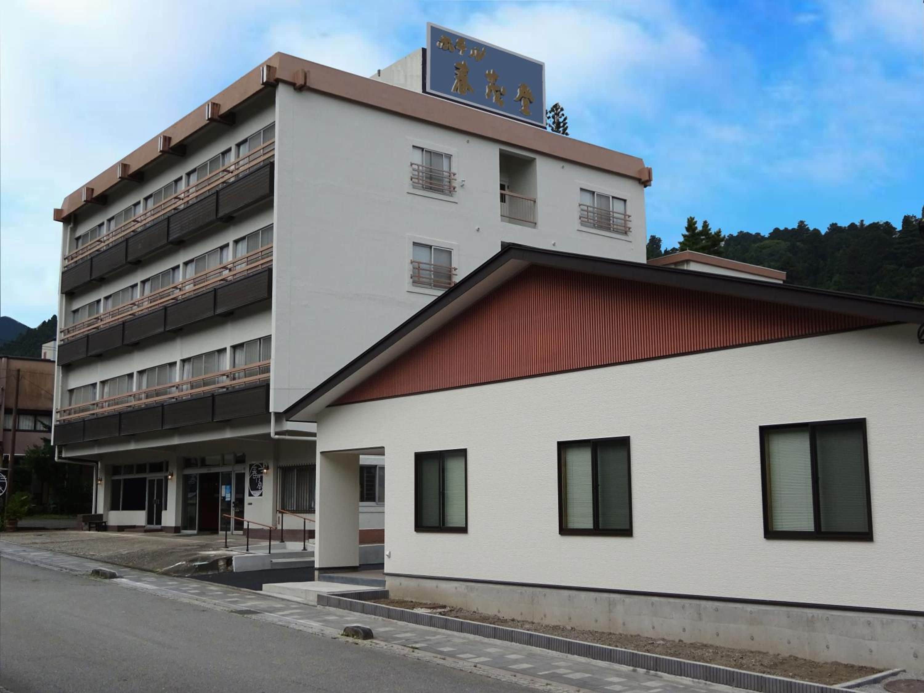 Um edifício com vários andares, teto plano e uma placa sobre a entrada.