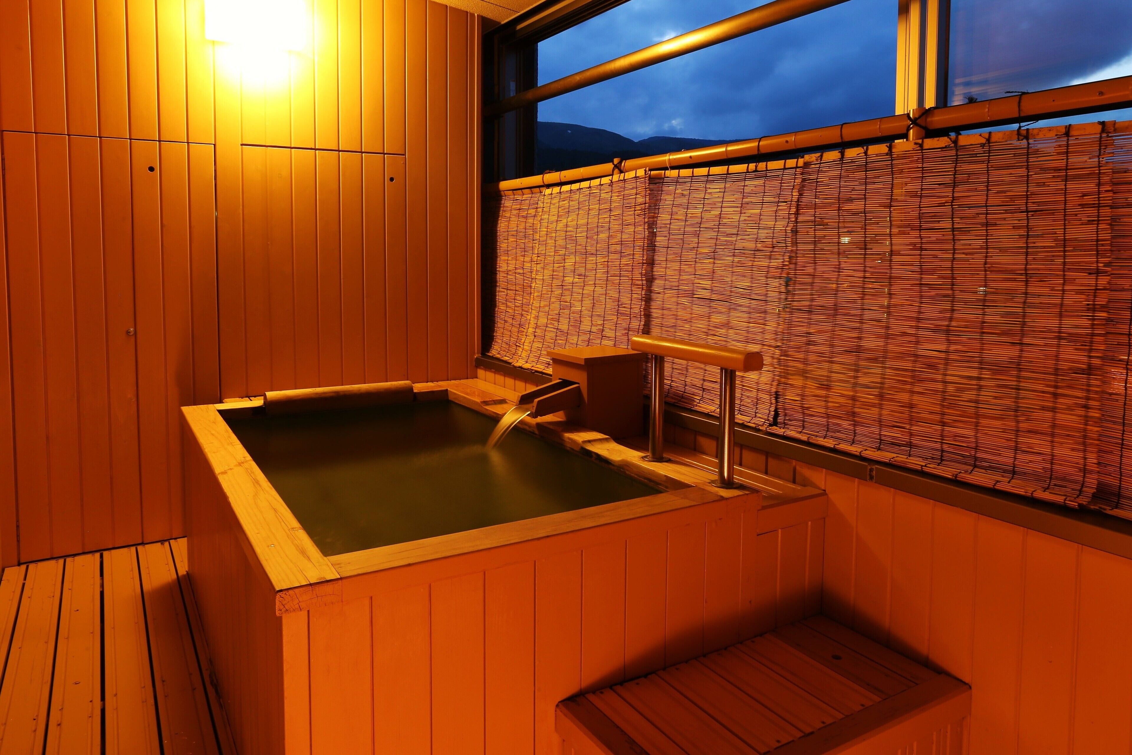 Uma sauna de madeira com janela, um banco e uma pequena mesa.
