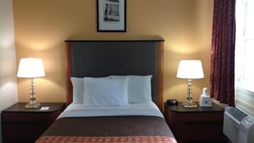 Quarto de hotel com uma cama, duas mesas de cabeceira, um quadro na parede e uma janela com cortinas.