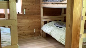 Quarto com beliches, paredes de madeira e uma janela.