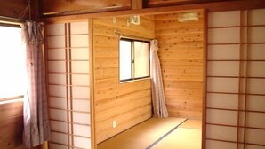 Um quarto japonês tradicional com tatames, uma porta deslizante e uma janela com cortinas.