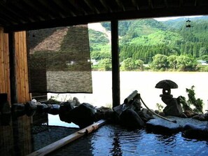 Quarto com vista para um lago e montanhas, uma escultura de pedra e uma estrutura de madeira.