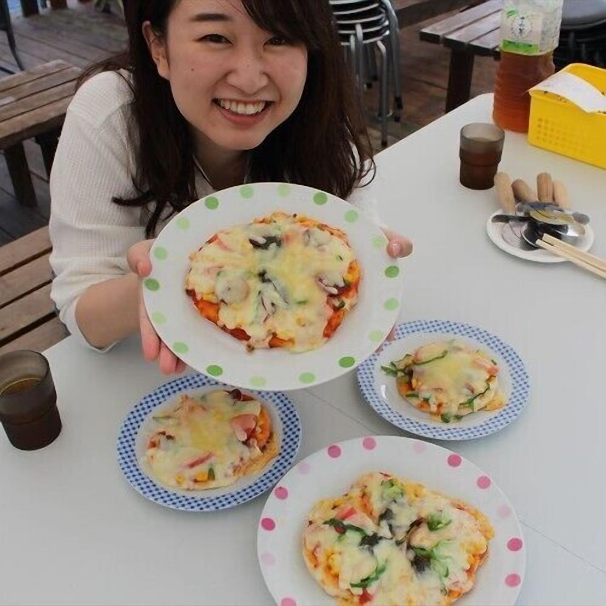 Uma pessoa segurando um prato com um alimento, possivelmente uma pizza, em uma mesa com outros pratos e uma bebida.