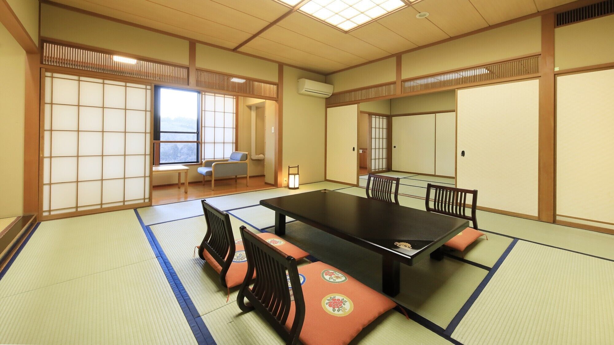 Um quarto japonês tradicional com tatames, uma mesa baixa e portas deslizantes.