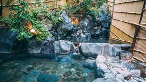 Um jardim japonês tradicional com lago límpido, pedras grandes e cerca de bambu.