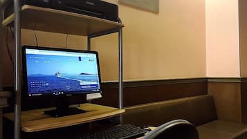 Configuração de computador sobre uma mesa de madeira, incluindo monitor, teclado e rato.