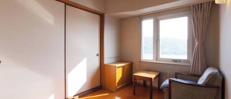 Quarto com porta deslizante, uma mesinha, um sofá e janela com cortinas.