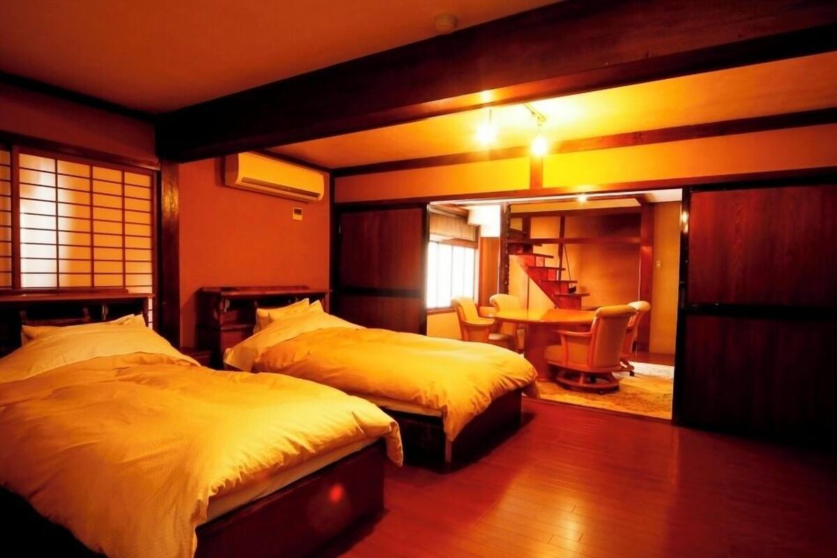 Quarto de hotel com duas camas, área de refeições e escada.