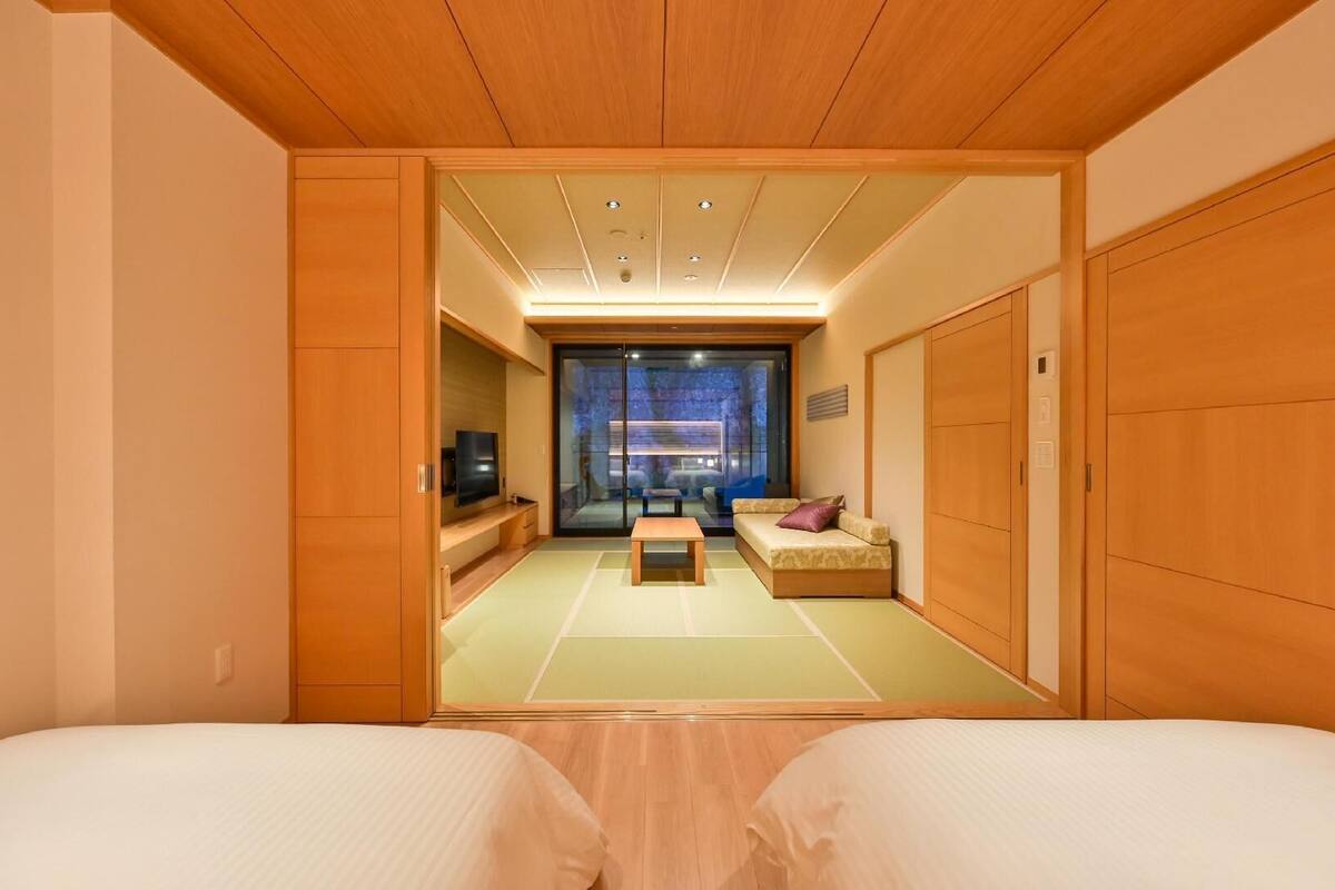 Quarto moderno com televisão, sofá e portas de correr que dão para uma varanda.