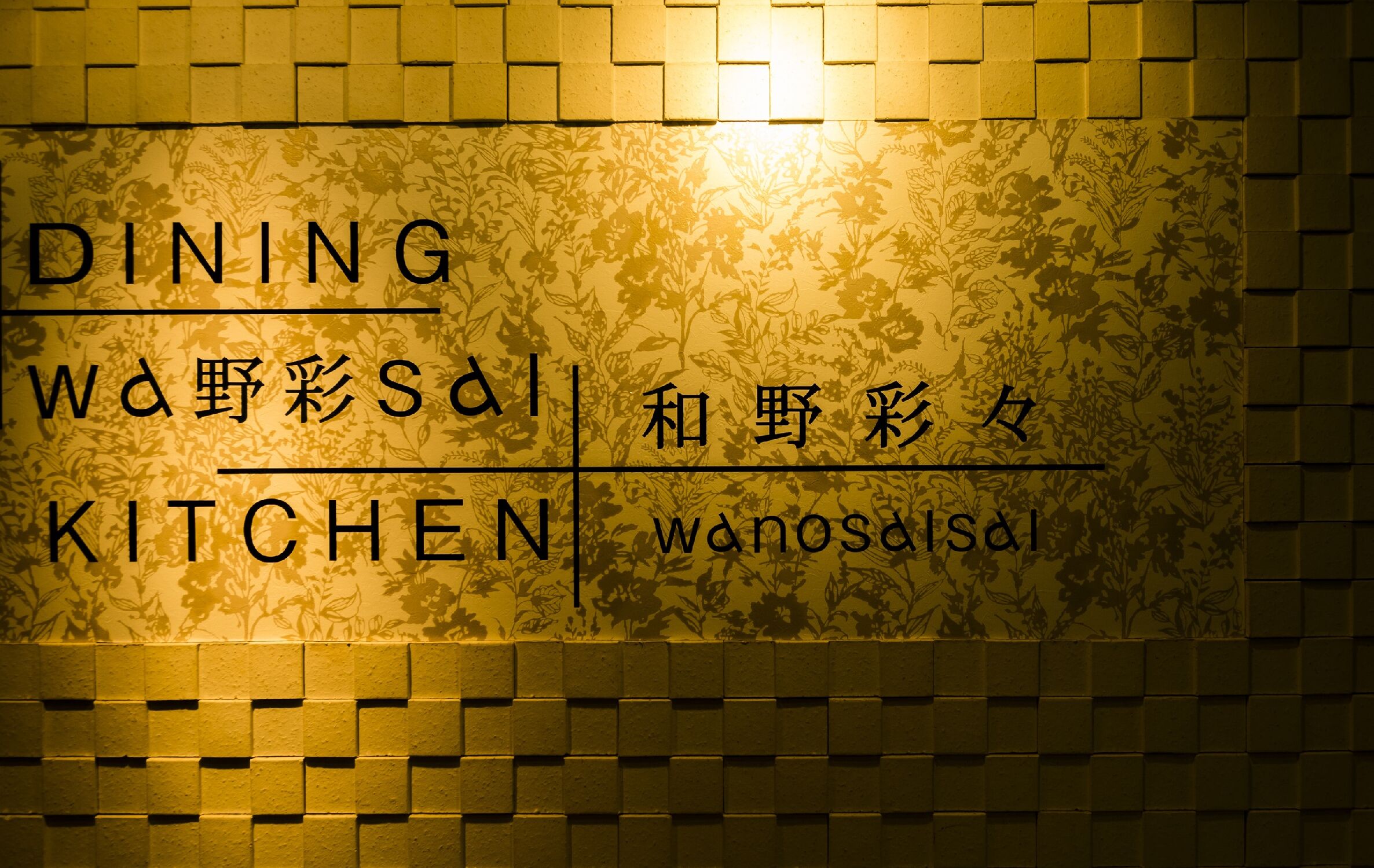 Parede com padrão floral e texto identificando uma área de refeições e cozinha.